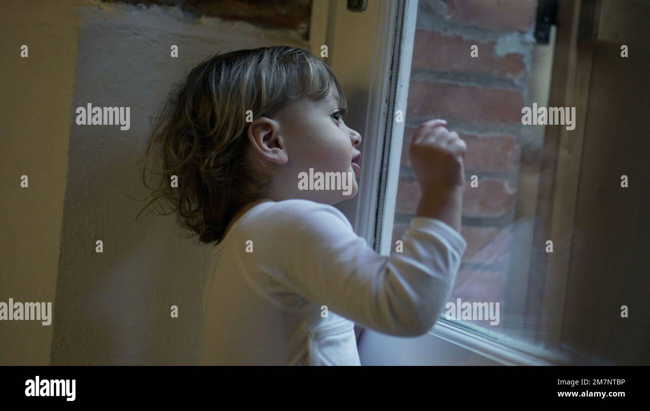 Child boy standing by window pointing at something outside Stock Photo ...