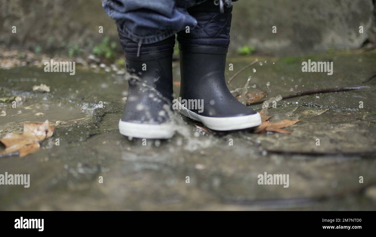 Child jumping into water puddle. Toddler wearing boots splash into puddle Stock Photo - Alamy