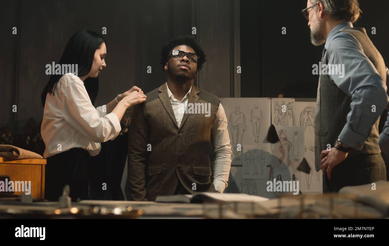 Female tailor measures sleeve of tailored suit, discusses with client ...