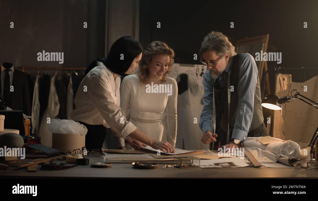 Cinematic shot of tailors and woman discussing sketches of wedding ...