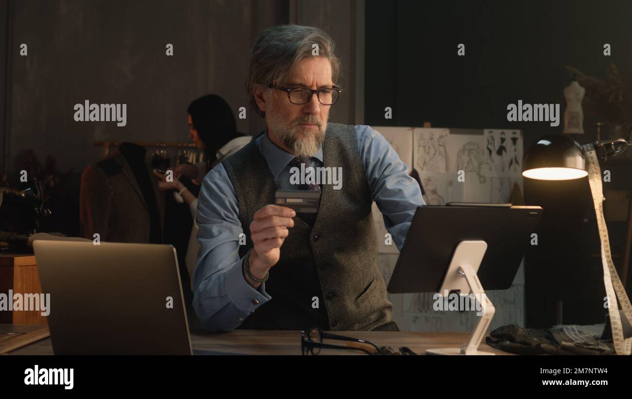 Tailor using tablet, transferring money on bank card, paying for ...