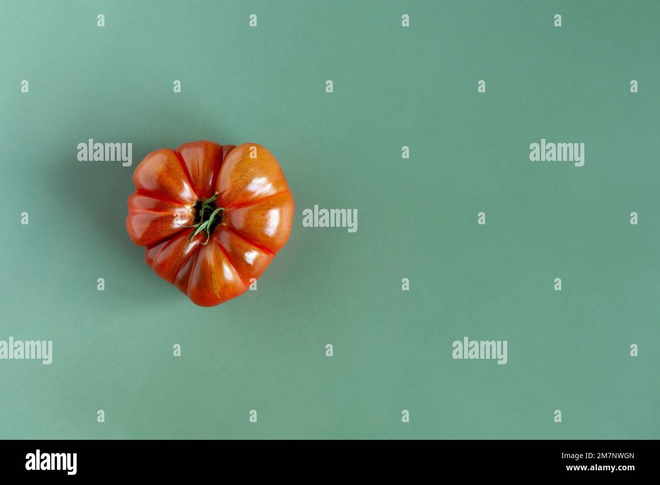 heart shape tomato on light green background, top view, copy space ...