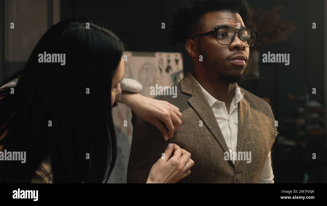 Female tailor measures tailored suit, discusses with client size and ...