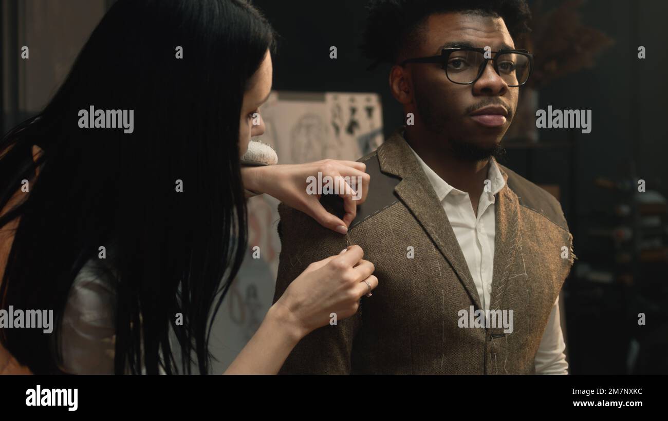 Female tailor measures tailored suit, discusses with client size and ...