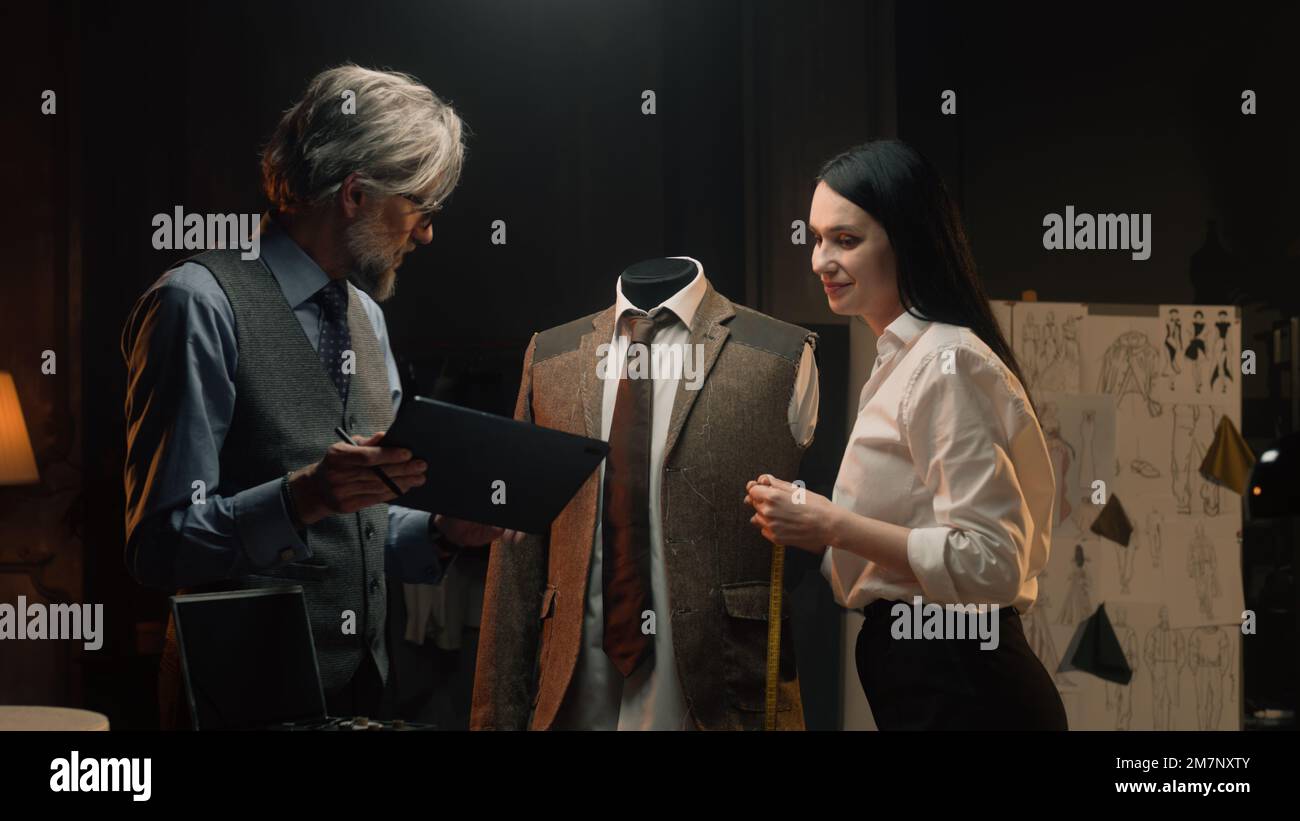 Male and female tailors work on business or wedding suit. Man draws ...