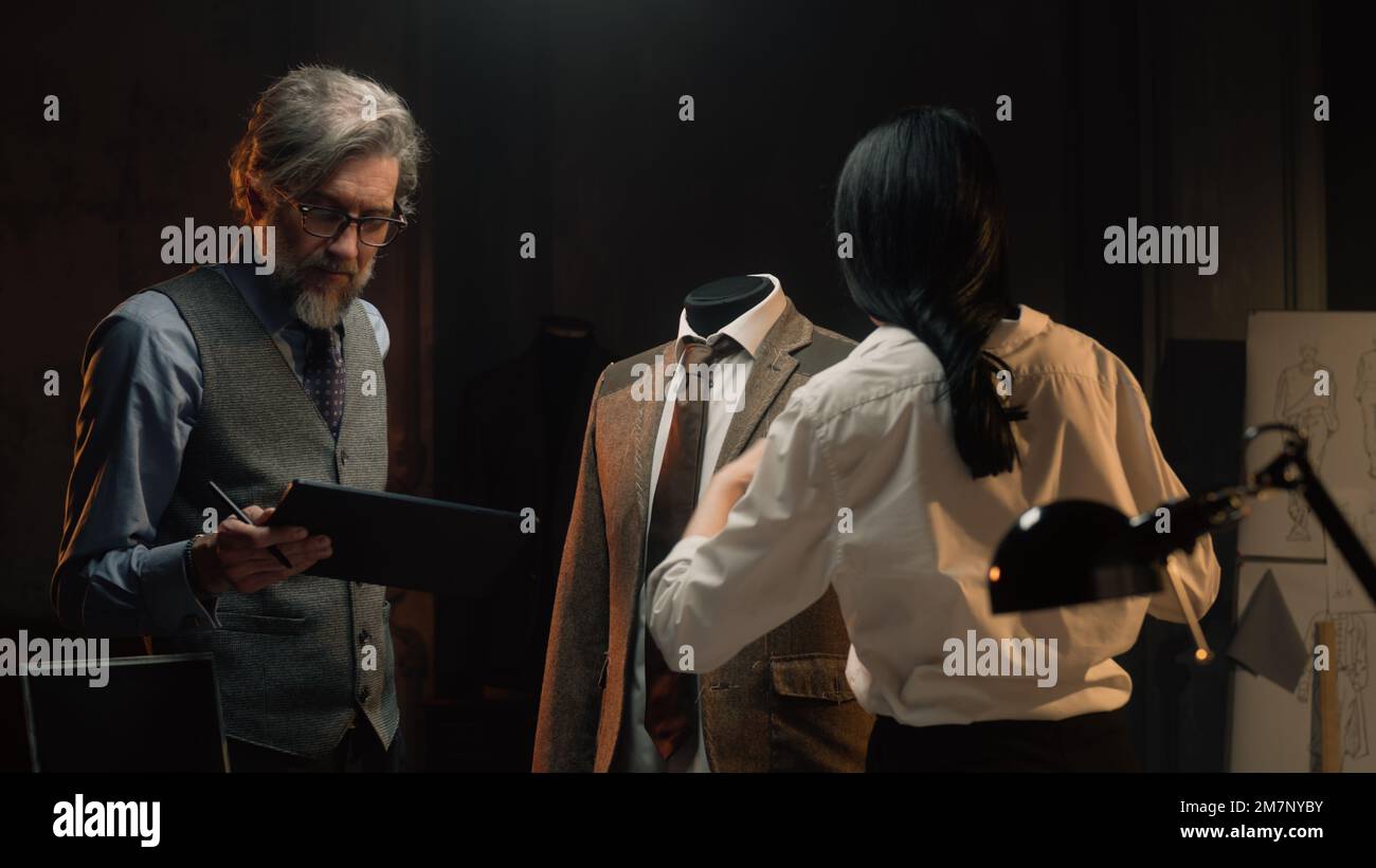 Male and female tailors work on business or wedding suit. Man draws ...