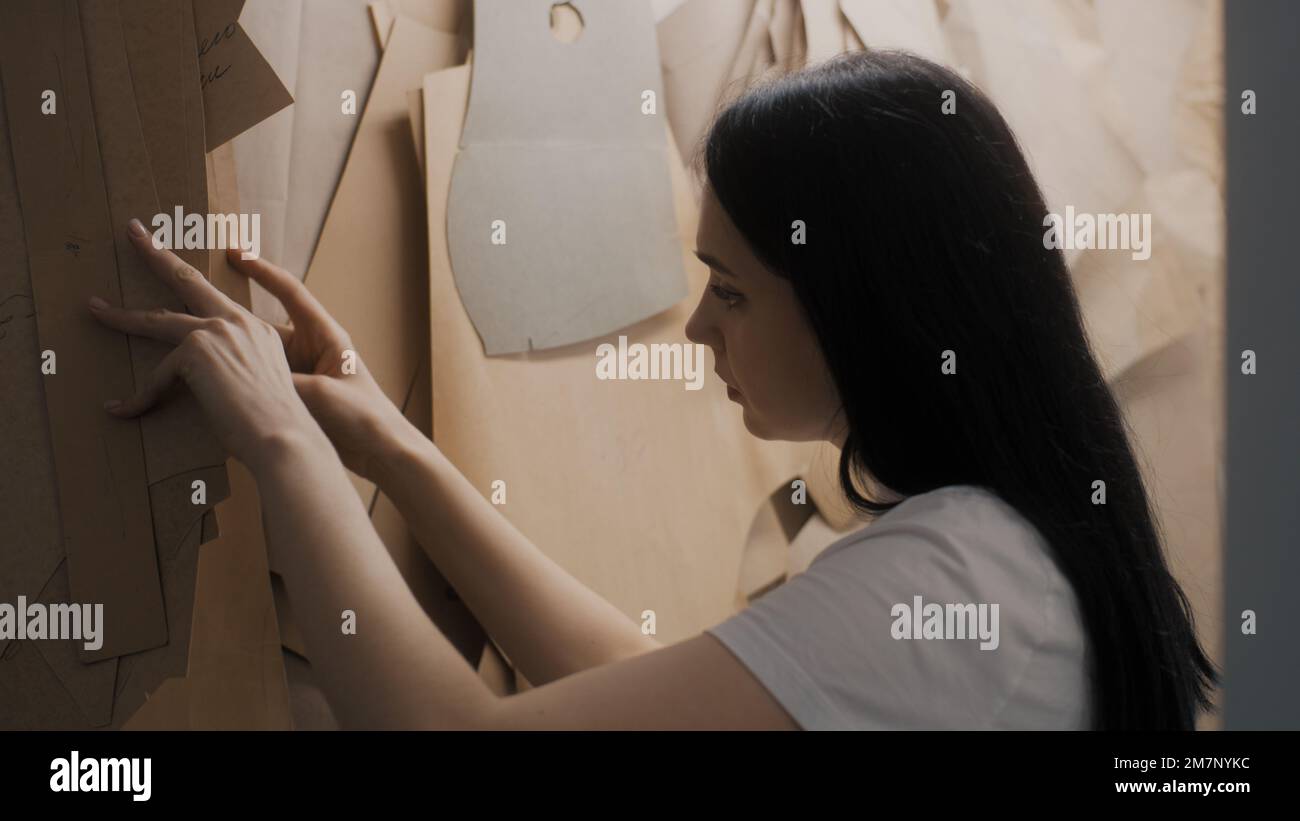 Female dressmaker chooses pattern for tailoring new clothes collection ...