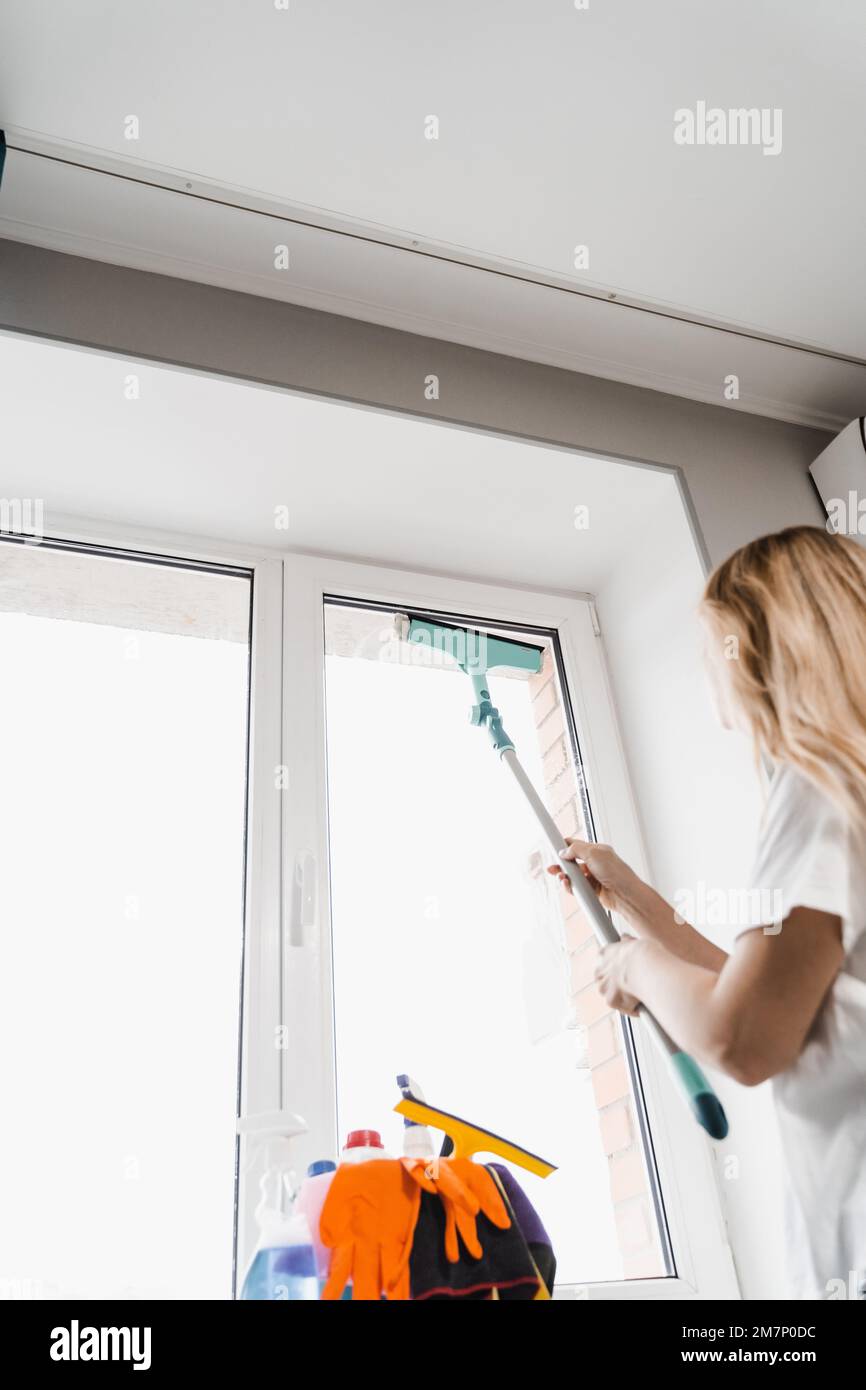 Windows cleaning service. Housewife is doing chores and washing windows ...