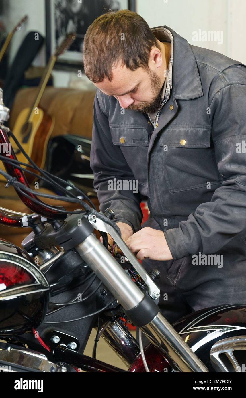 The mechanic connects the electrical cables of the motorcycle. Vertical ...