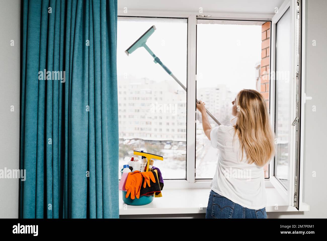 Windows cleaning service. Housewife is doing chores and washing windows indoor in apartment ...