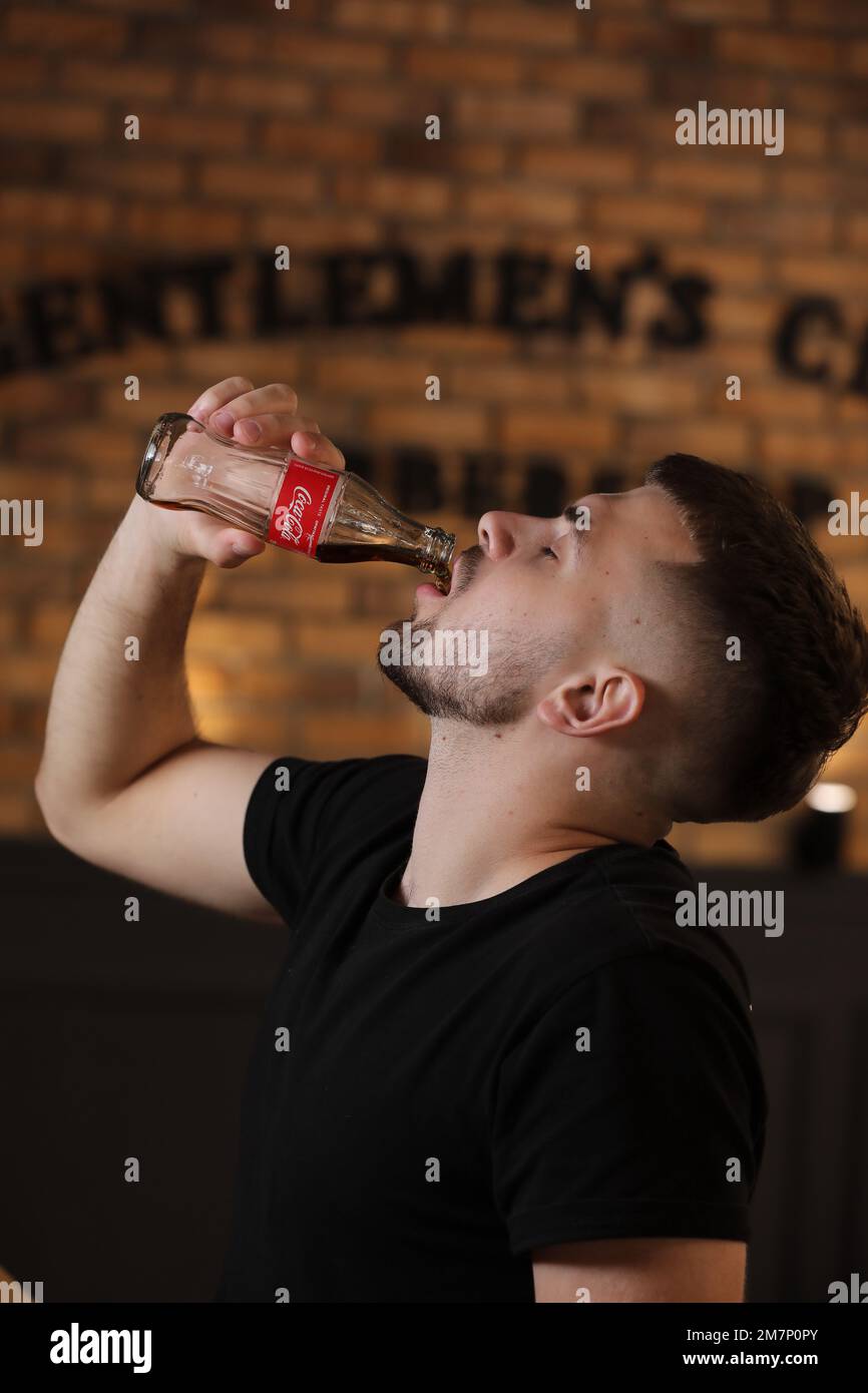 RIVNE, UKRAINE JUNE 26 2020: young bearded man drinking coca cola from ...
