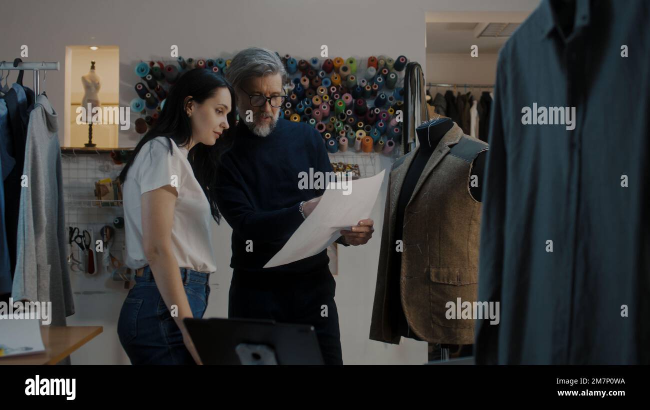 Male mature fashion designer discusses sketch drawing of future suit ...