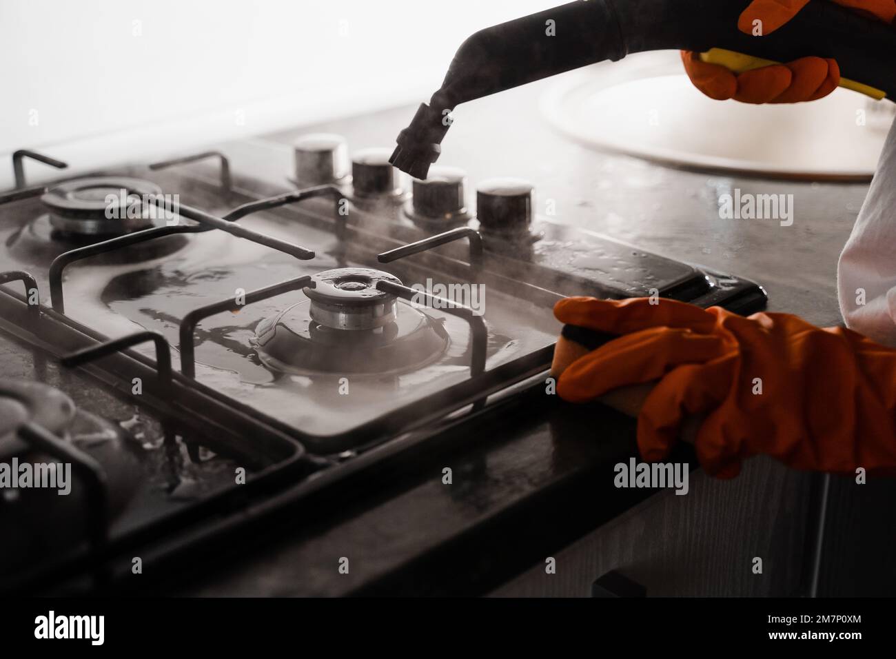 Steam cleaning of cooker in kitchen close-up. Worker of cleaning ...