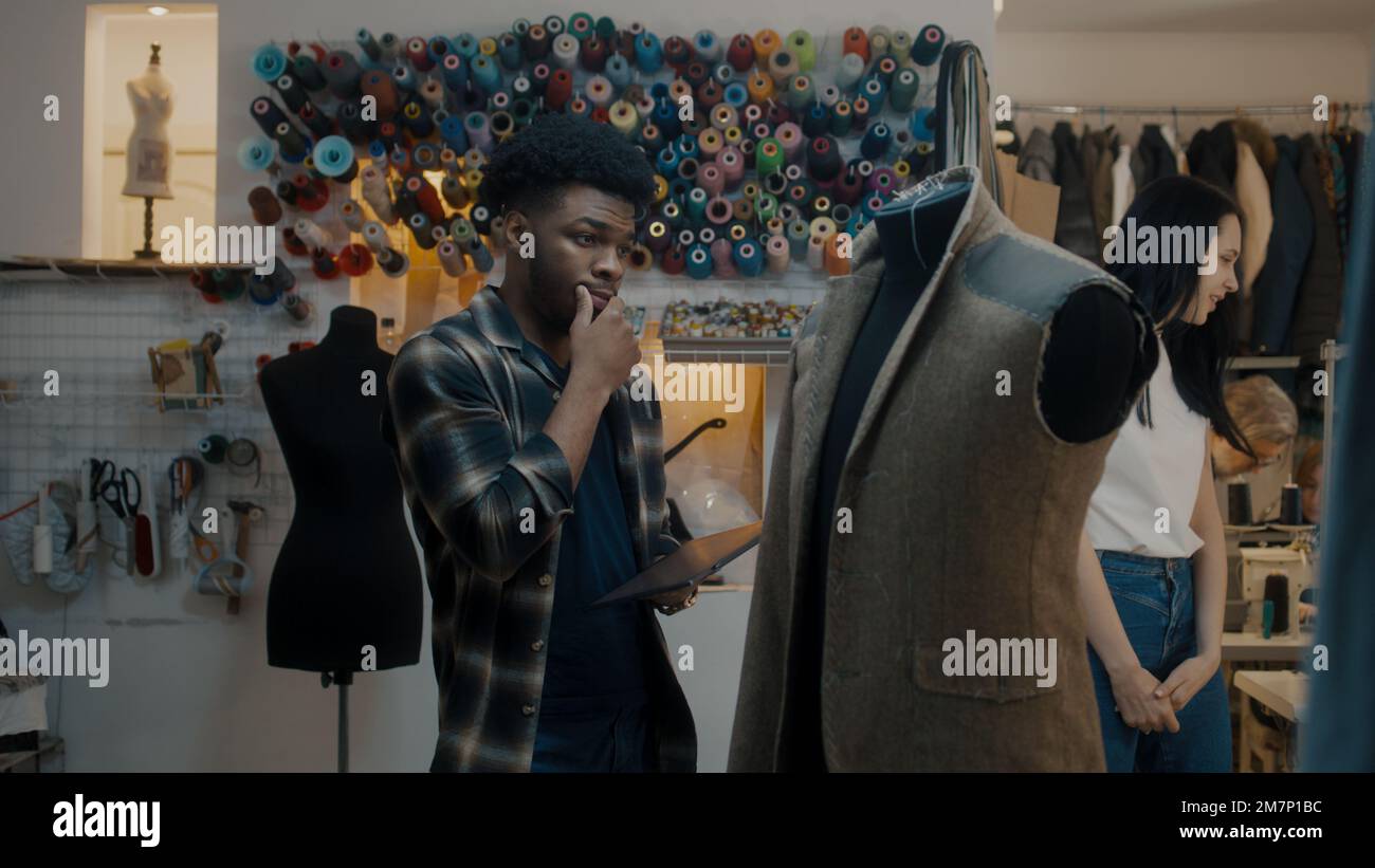 African American fashion designer stands near the mannequin in ...