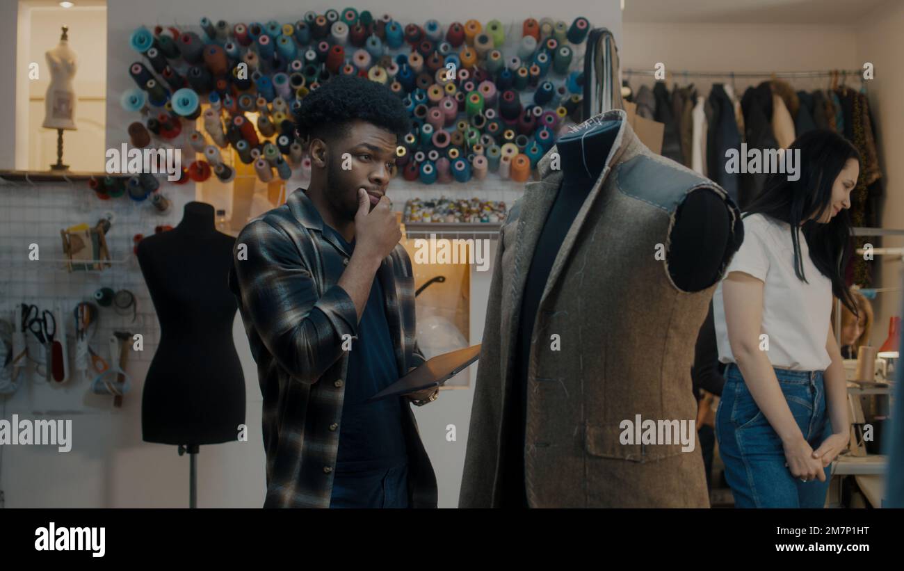 African American fashion designer stands near the mannequin in ...