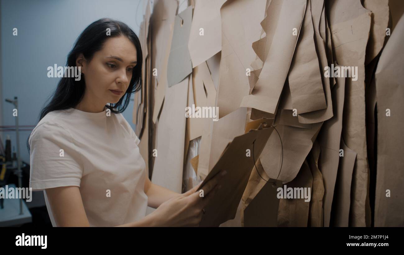 Female tailor chooses pattern for tailoring new clothes collection ...