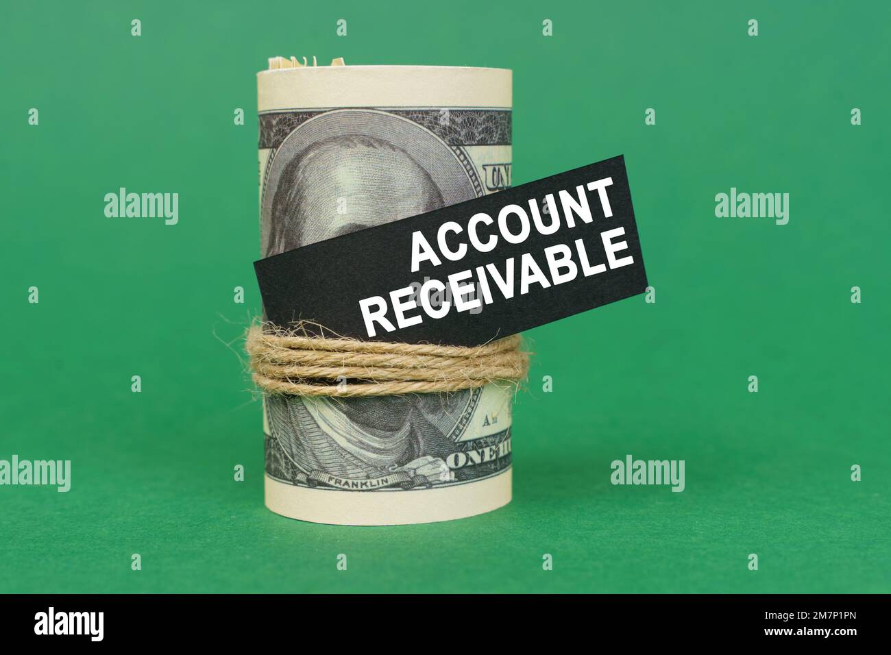 Business concept. On a green surface, rolled dollars with a black sign ...