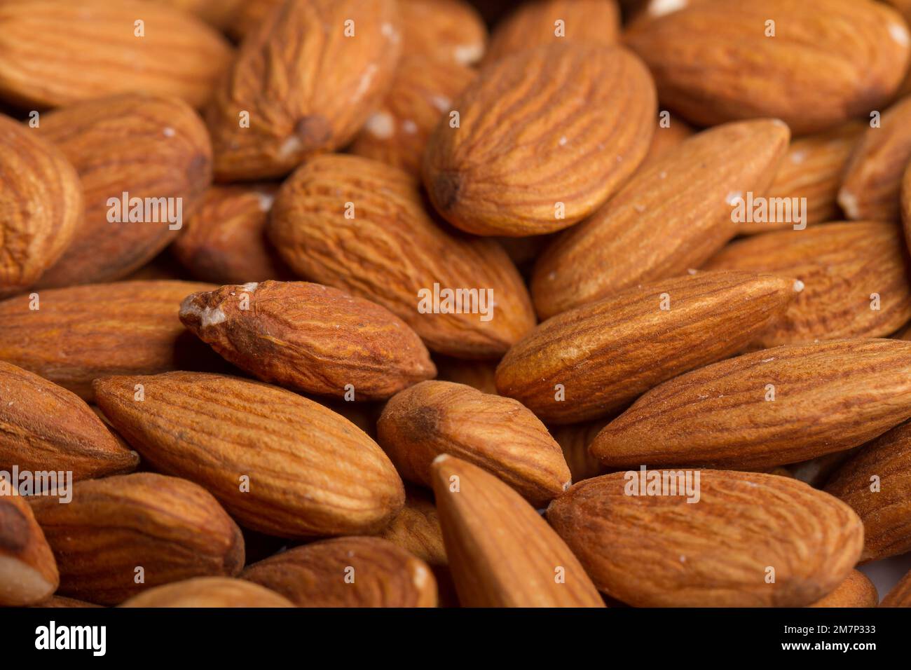Close up on almonds resting on a flat background Stock Photo - Alamy