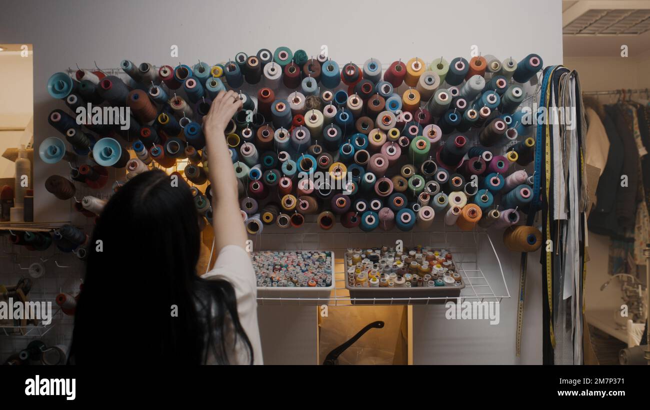 Fashion designer chooses color of threads for tailoring new wedding suit. Tailor takes skeins of ...