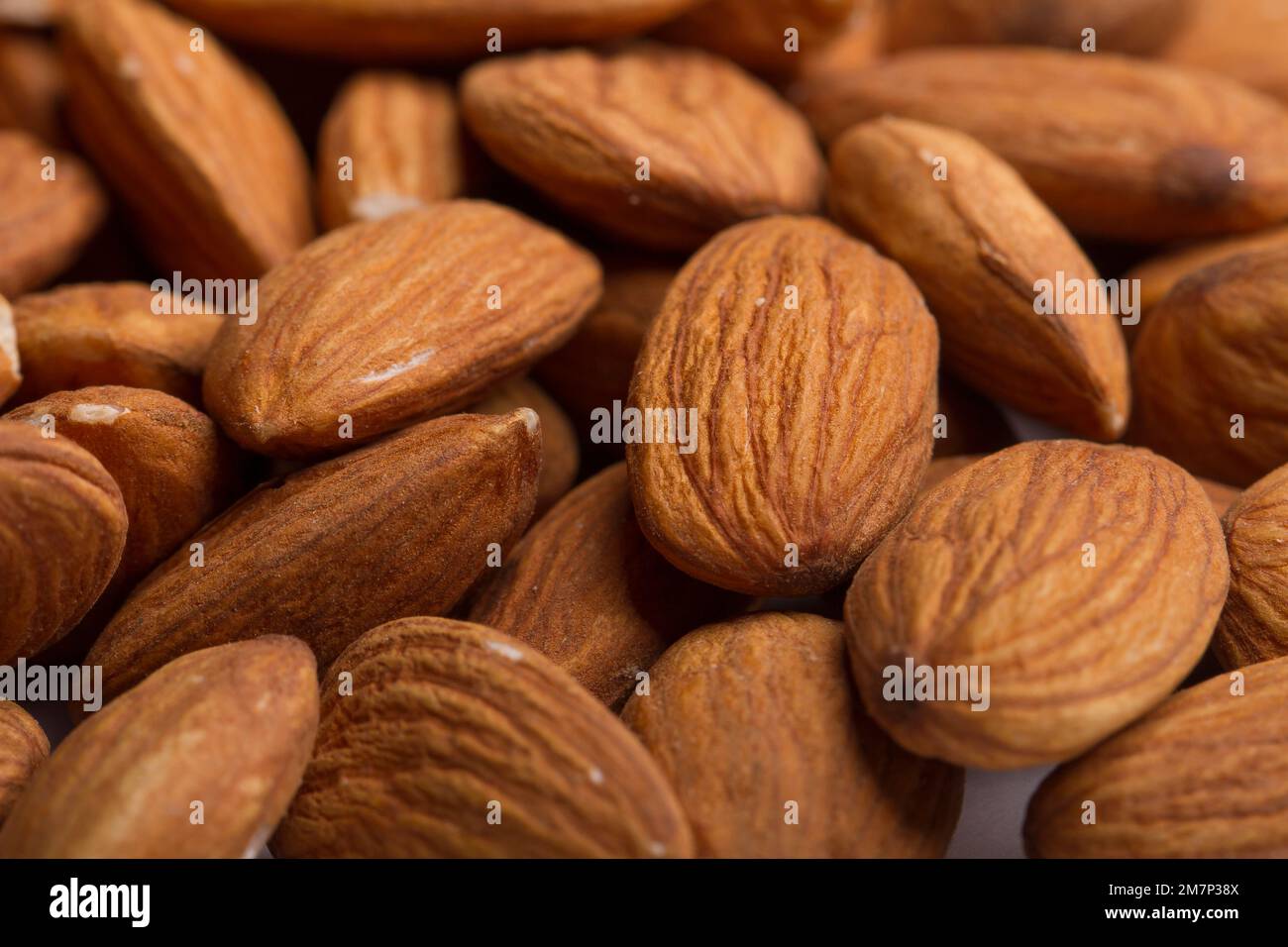 Close up on almonds resting on a flat background Stock Photo - Alamy