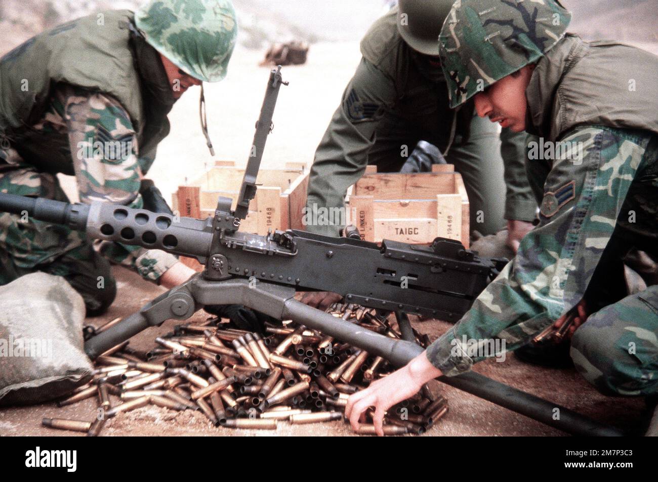 Security policemen pick up brass shell casings after firing an M-2 .50 ...