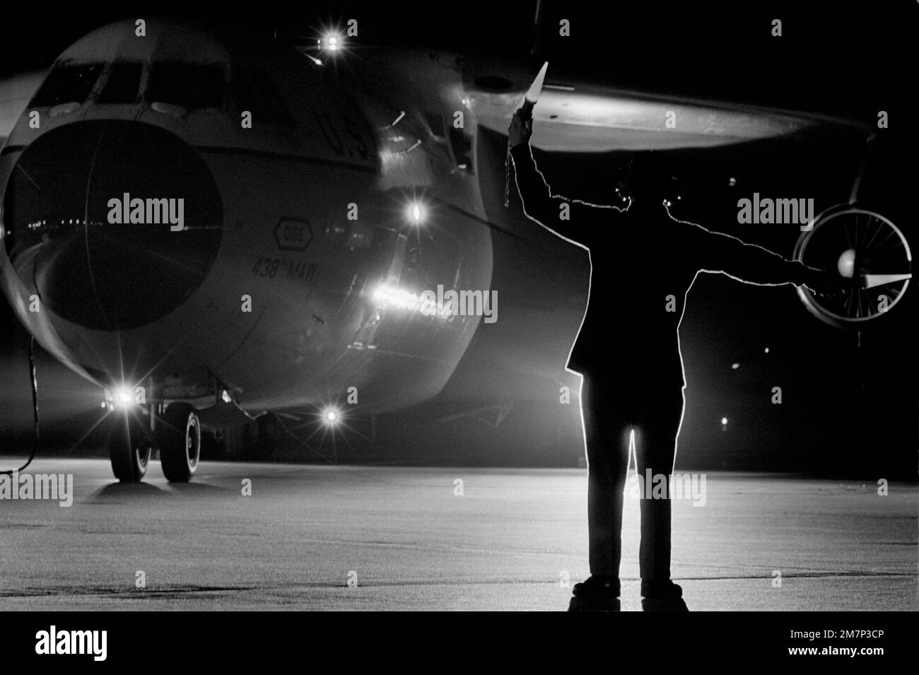 A ground crewman, using illuminated wands, marshals a C-141 Starlifter ...