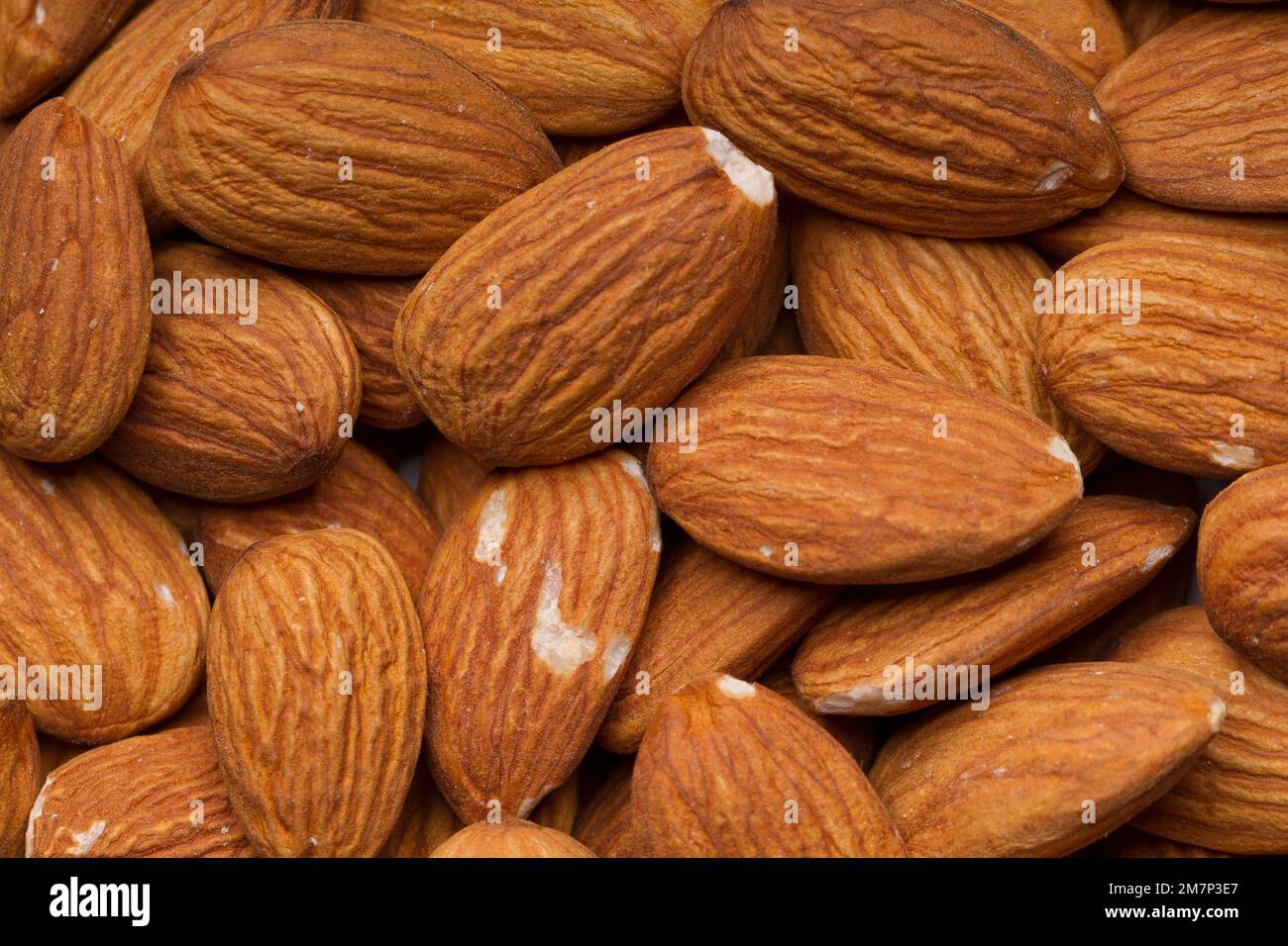 Close up on almonds resting on a flat background Stock Photo - Alamy