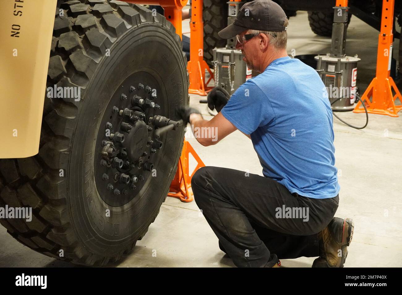 A student taking the JLTV Phase II course tightens the tire lug nuts ...