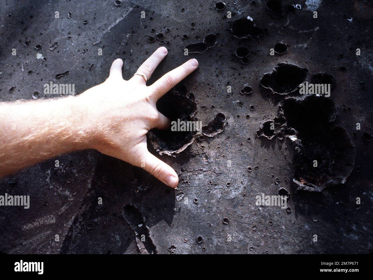 A close-up view of explosion holes on an armor-plated steel piece. The ...