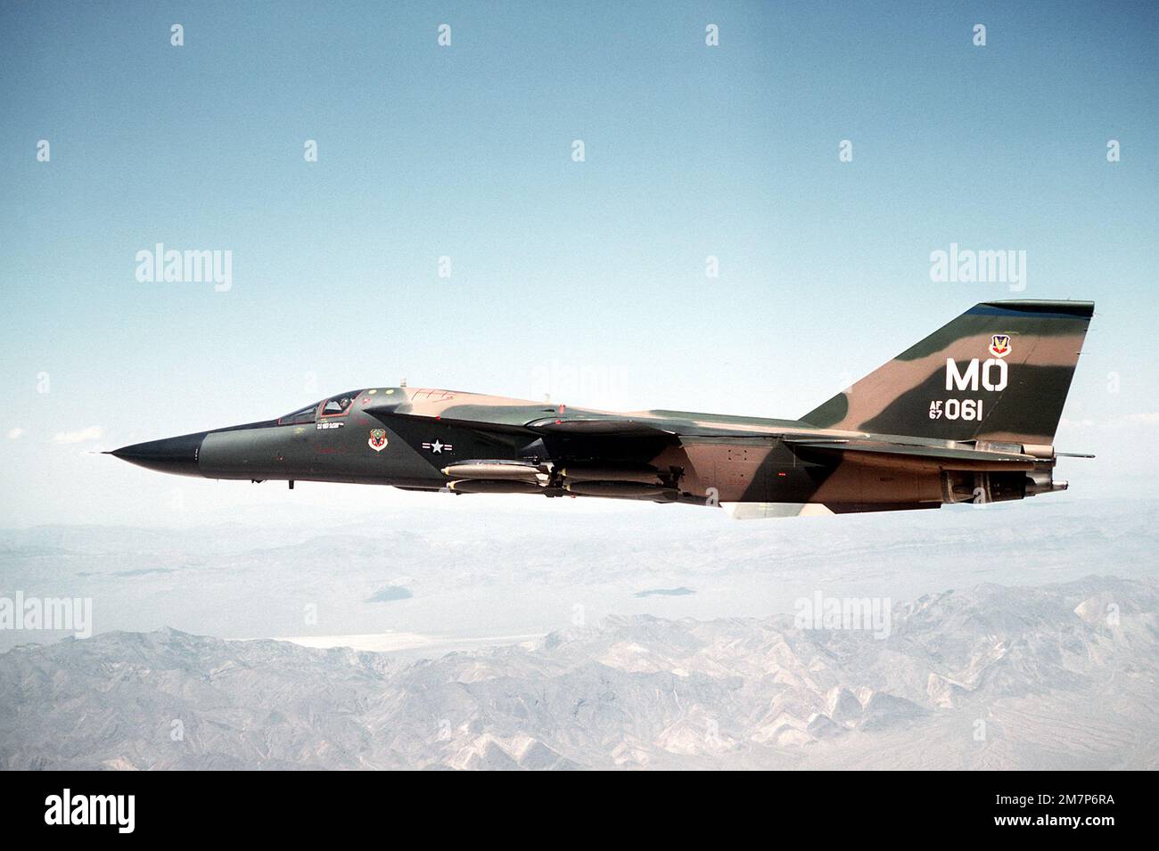 Left side view of an F-111 aircraft in flight over the Nellis Air Force ...