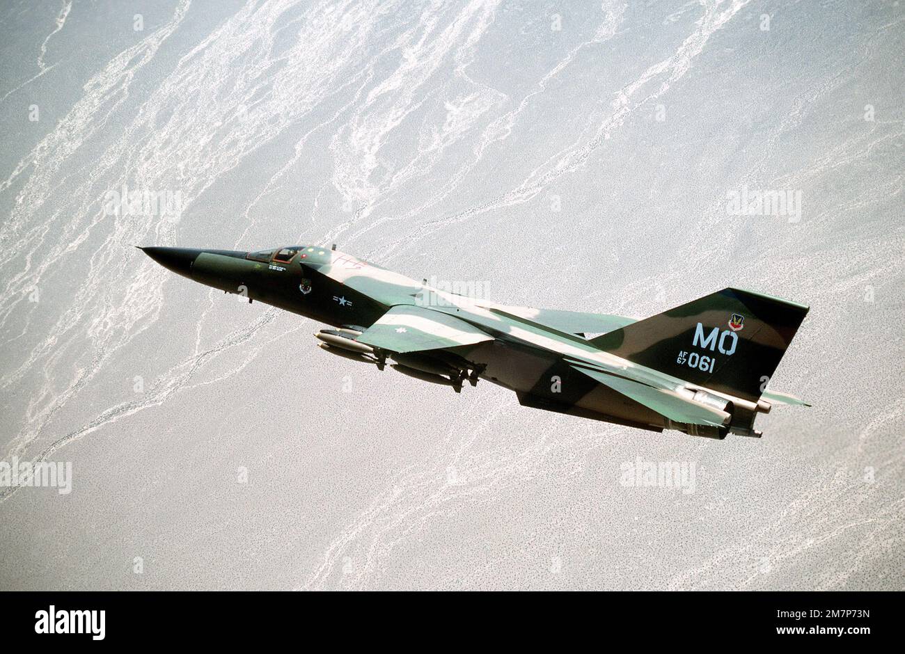 AN air-to-air left side view of an F-111A aircraft banking to the right ...