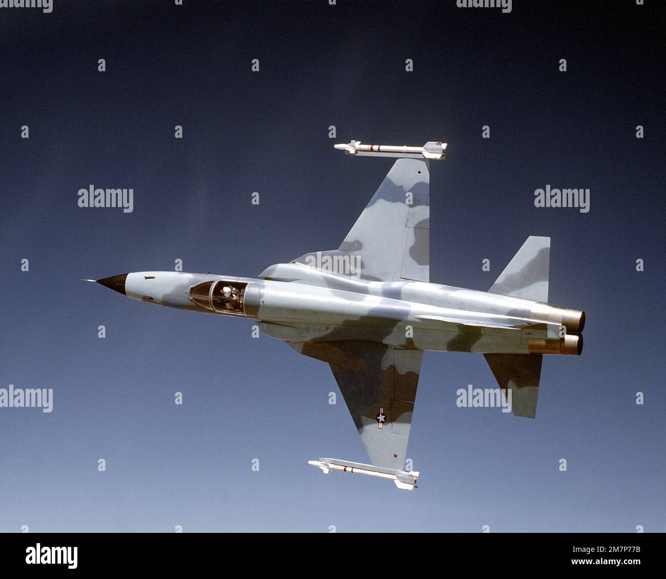 AN air-to-air top view of an F-5 Tiger II aircraft banking to the left ...