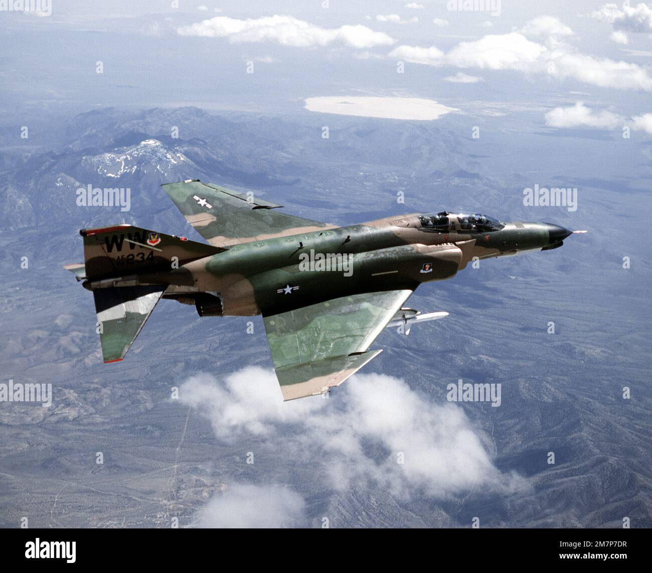 A right rear view of an F-4G Phantom II Wild Weasel aircraft banking to the right over a range ...