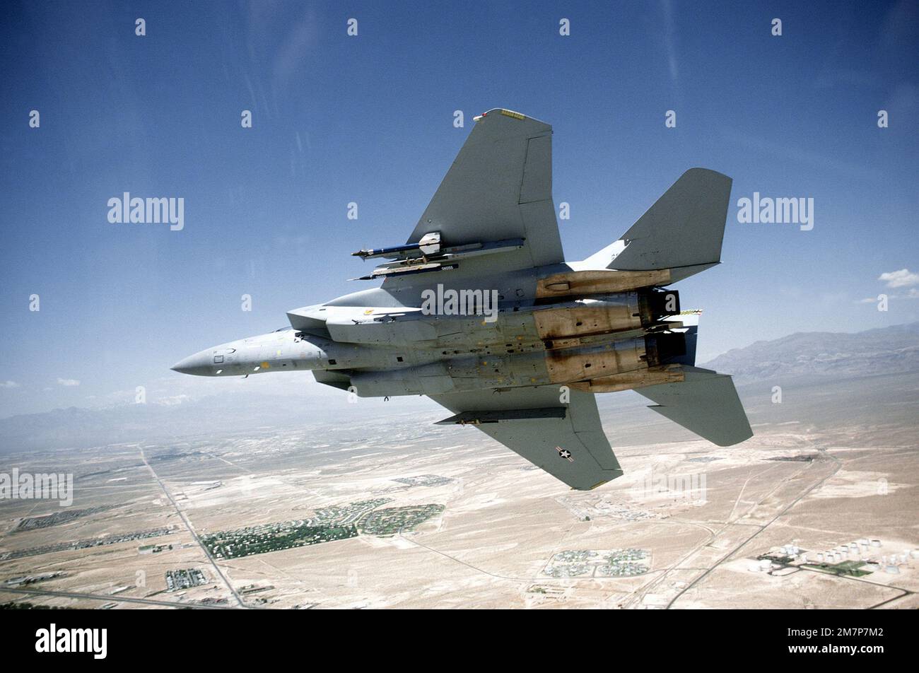 AN air-to-air underside view of an F-15 Eagle aircraft banking to the ...