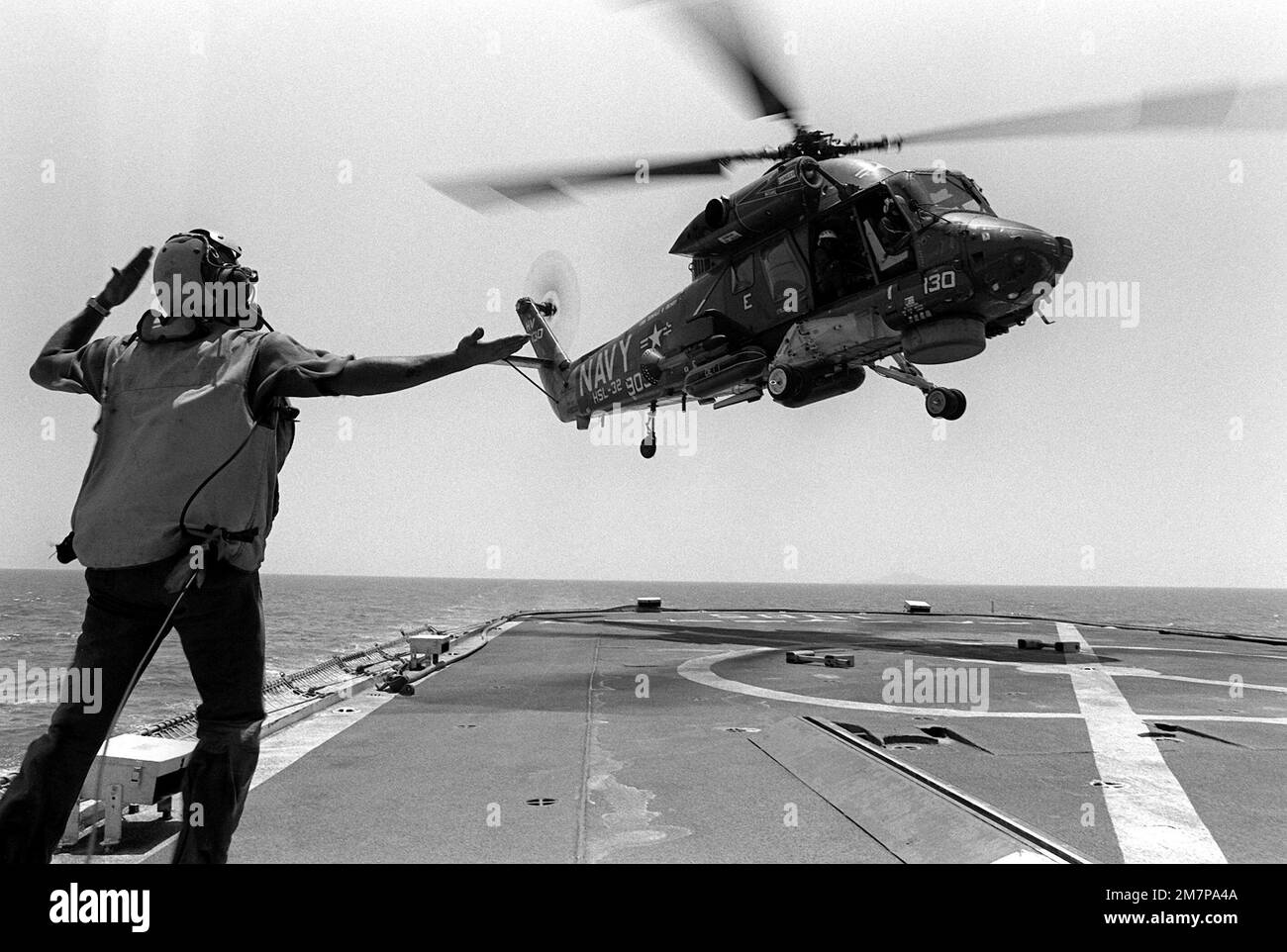 A flight deck crewman directs the pilot of an SH-2 Seasprite helicopter as the helicopter lands ...