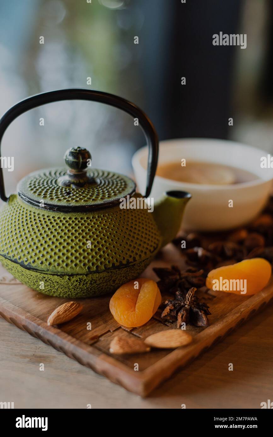 A close-up shot of a vintage green teapot and dry fruits and a tea with ...