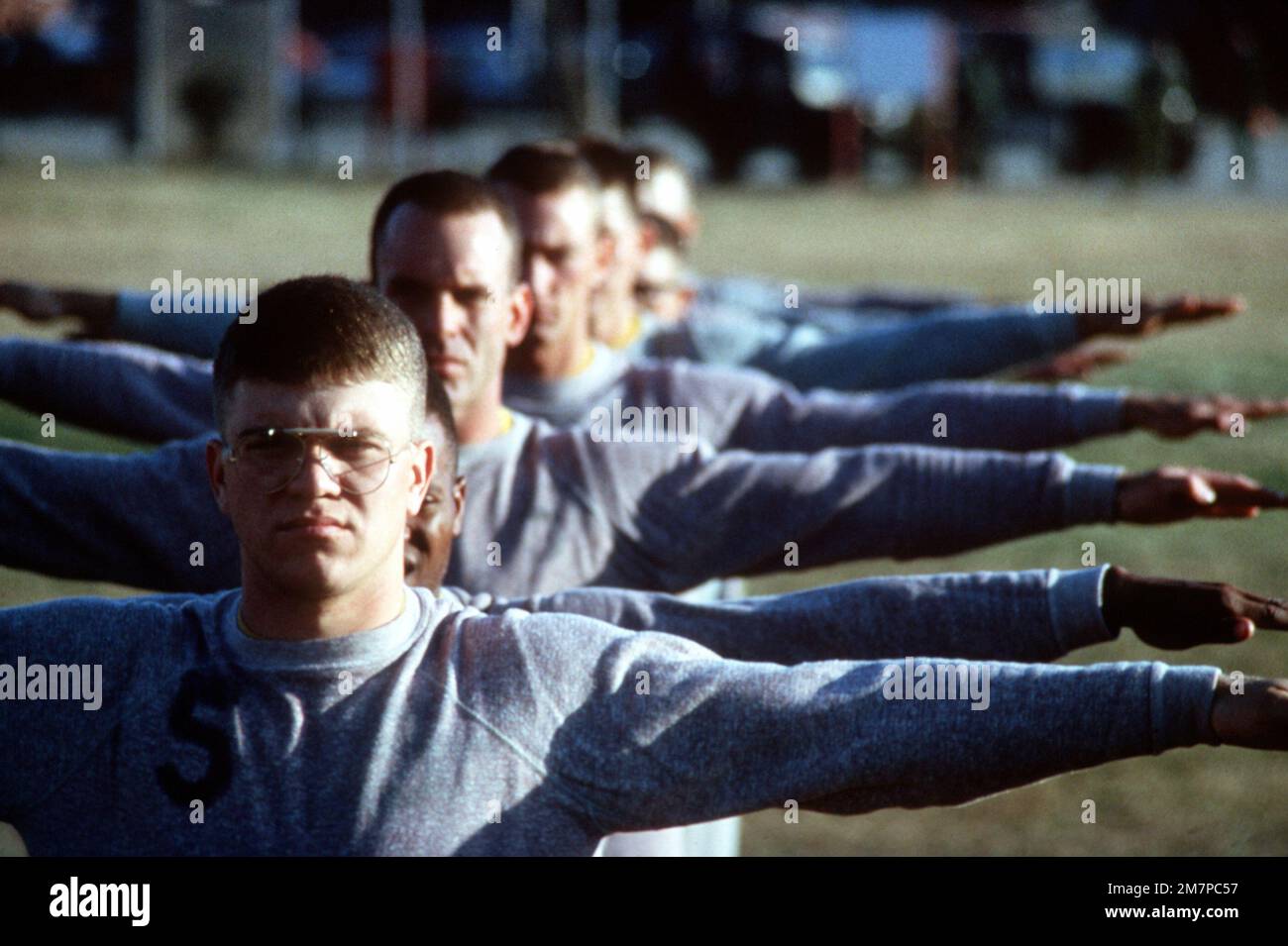 A column of Marine officer candidates prepare to do an arm exercise as ...