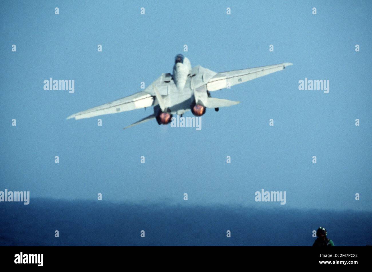 An F-14 Tomcat aircraft banks to the left after clearing the fight deck ...