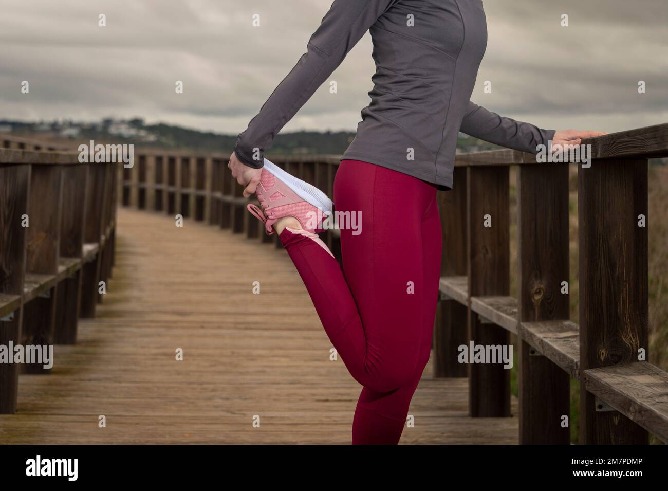 Close up of a woman runner doing a leg stretch warm up exercise outside ...