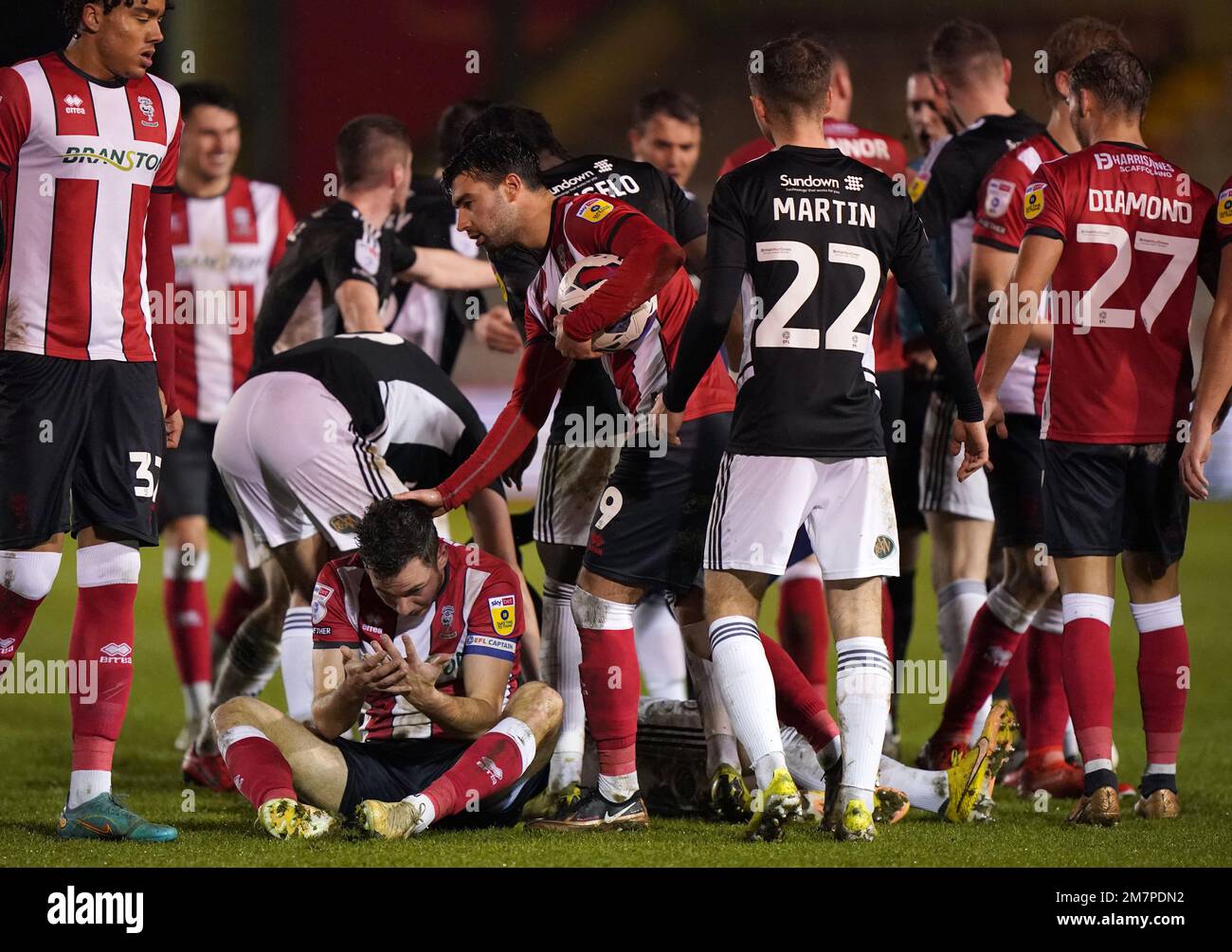 Lincoln City's Tom Hopper (sitting) reacts after a collision with ...