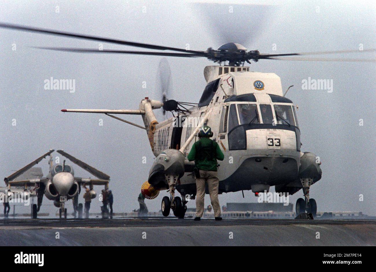 A plane director guides an SH-3 Sea King helicopter to a landing on the ...