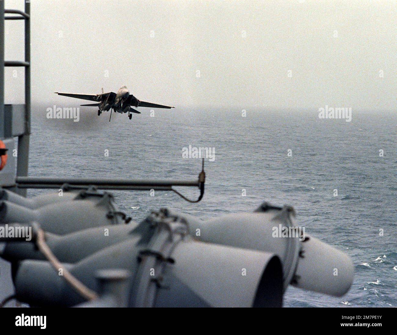 An F-14 Tomcat aircraft, with arresting hook lowered, approaches for a ...