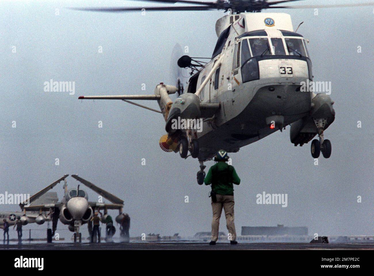 A plane director guides an SH-3 Sea King helicopter to a landing on the ...