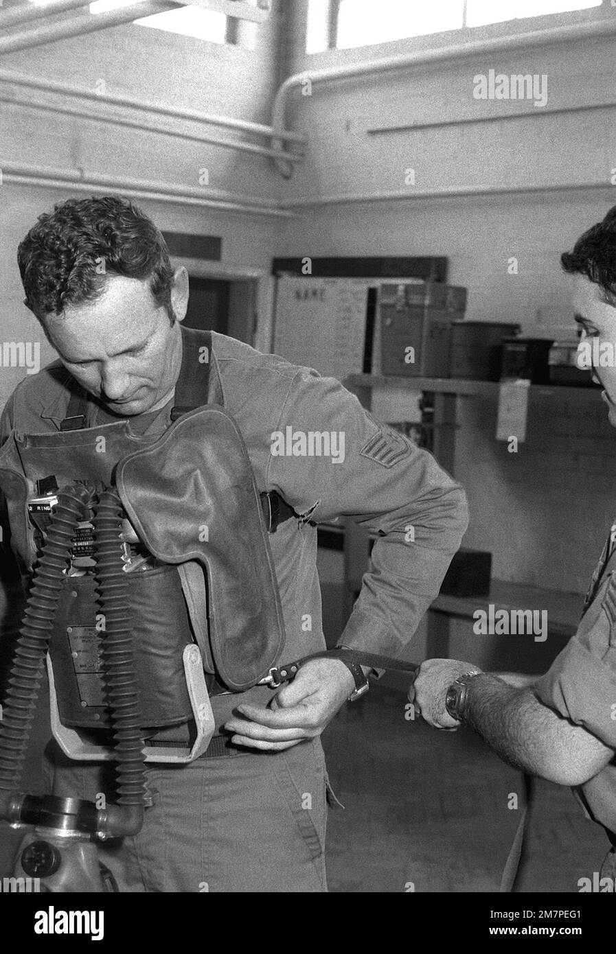 A staff sergeant dons his oxygen breathing apparatus with the help of ...