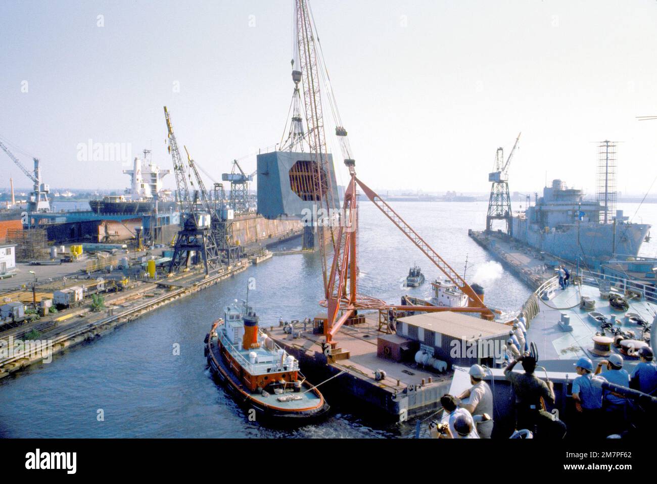 A lift barge/crane, being propelled by a tugboat on each side, carries ...
