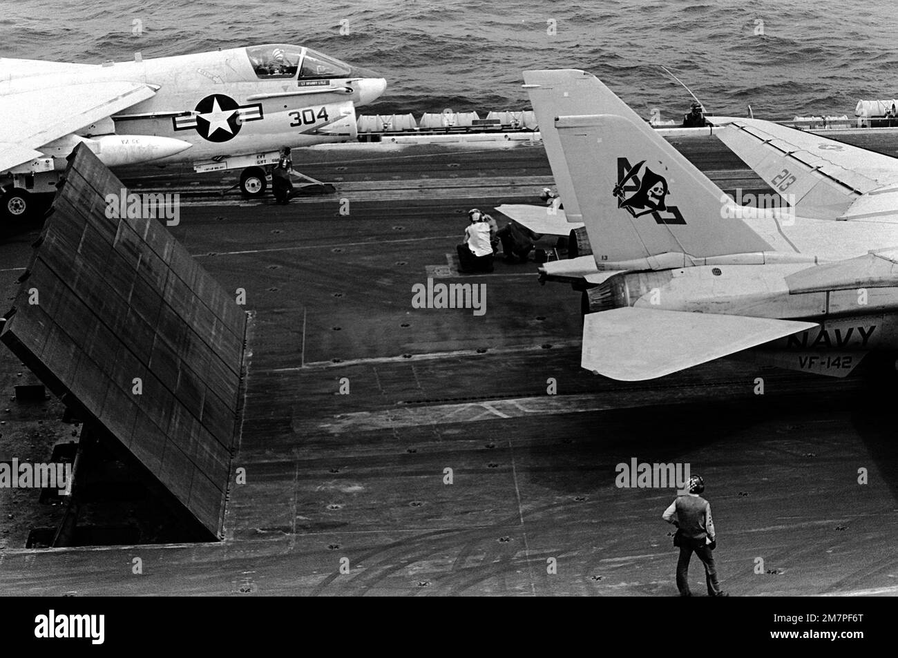 Three blast deflector panels are raised behind an F-14 Tomcat aircraft ...