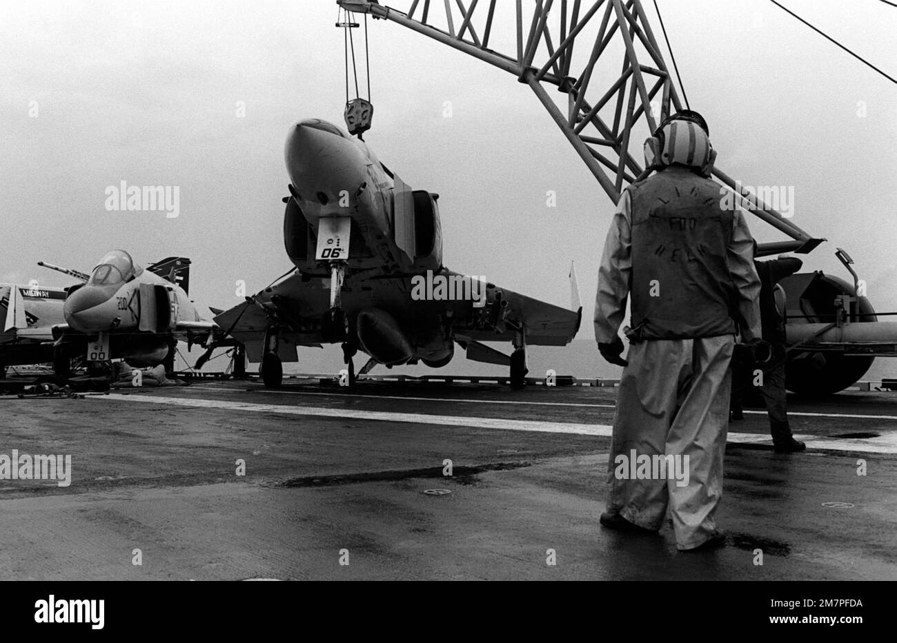 A crane is used to lift an F-4 Phantom II aircraft away from the port ...