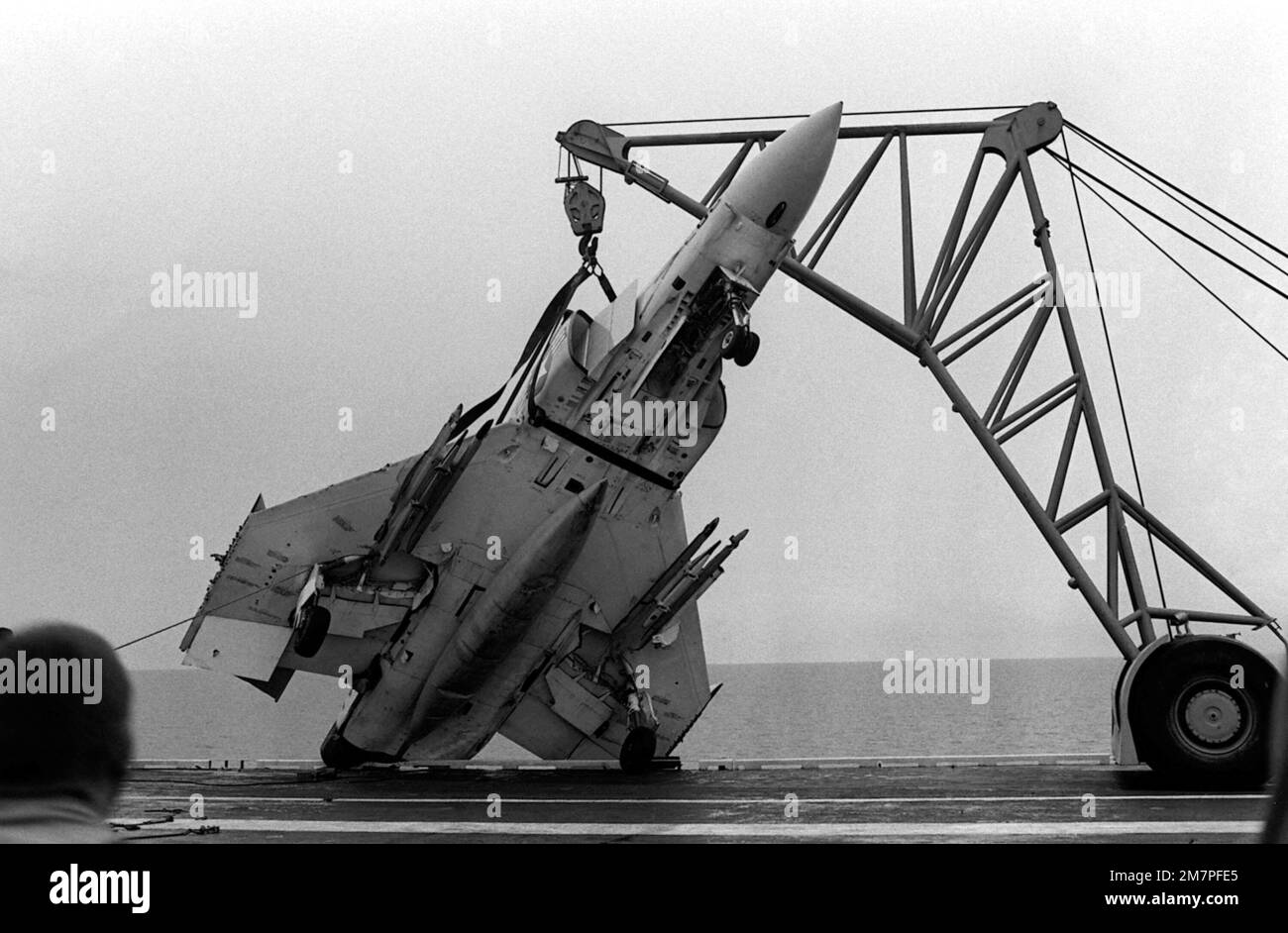 A crane is used to lift an F-4 Phantom II aircraft away from the port ...