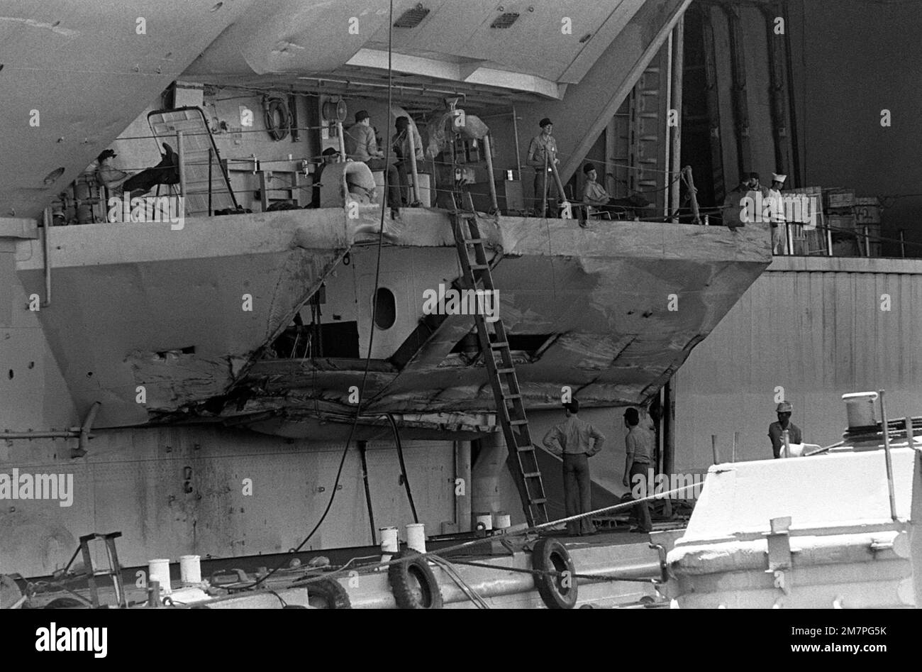 Workers make repairs on a port side section of the aircraft carrier USS ...