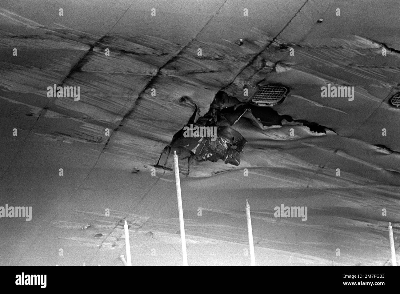 A view of damage caused to the port amidships section of the aircraft ...
